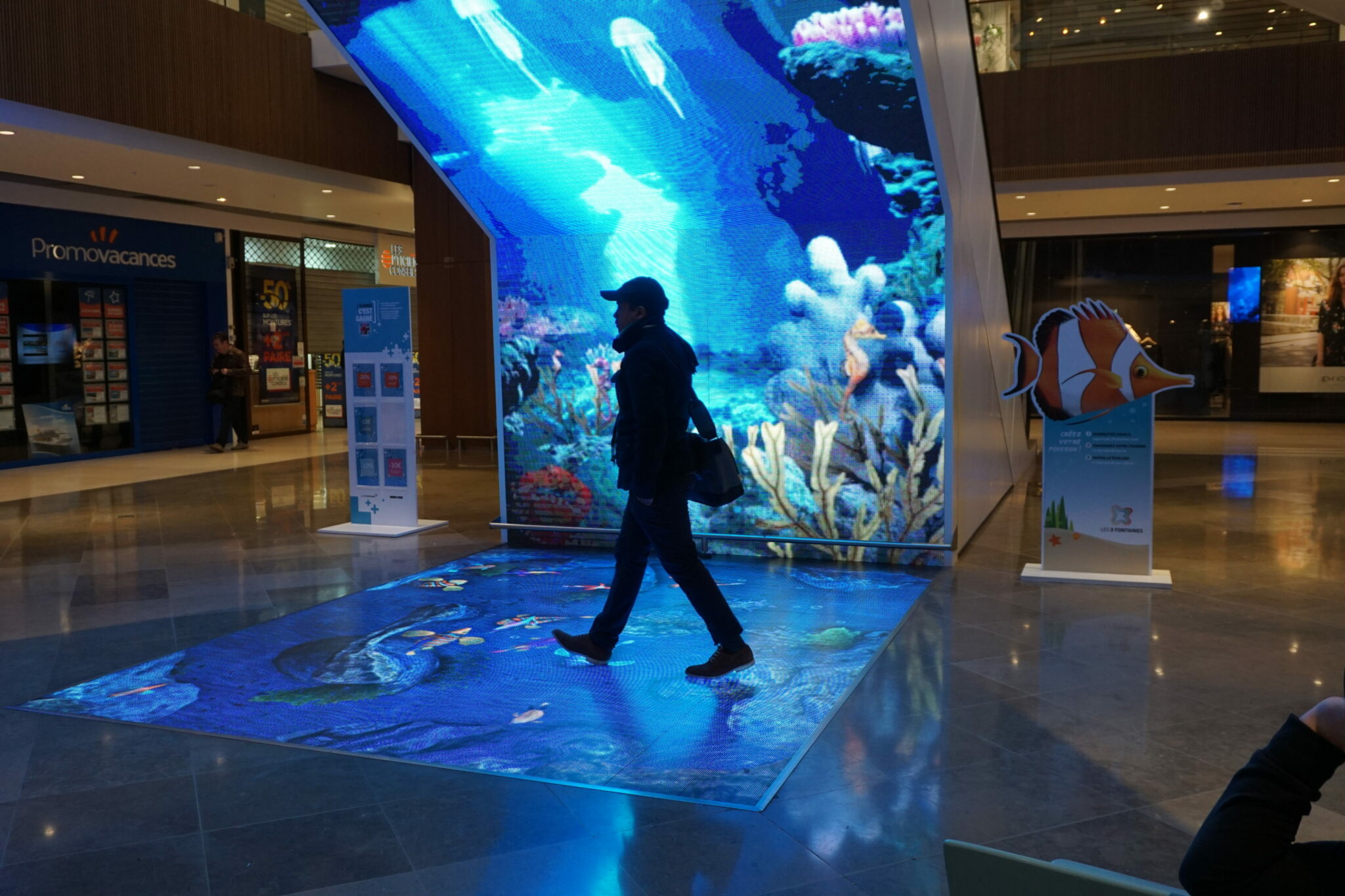 The 3Fontaines shopping mall featuring screens under an escalator